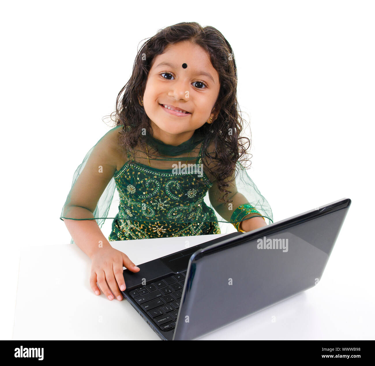 Little Indian girl using a laptop on table, isolated on white ...