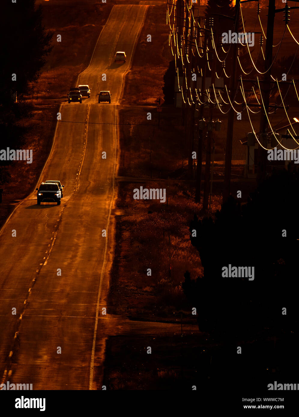 Cars driving on old country road at sunset of sunrise power lines Stock ...
