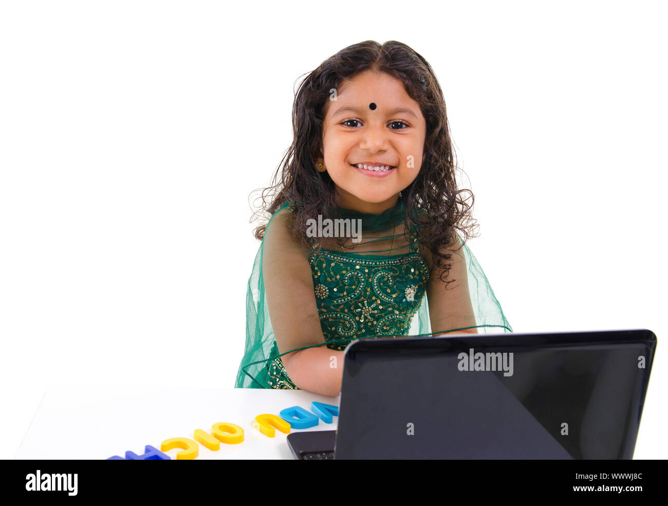 Little Indian girl using a laptop on table, isolated on white ...