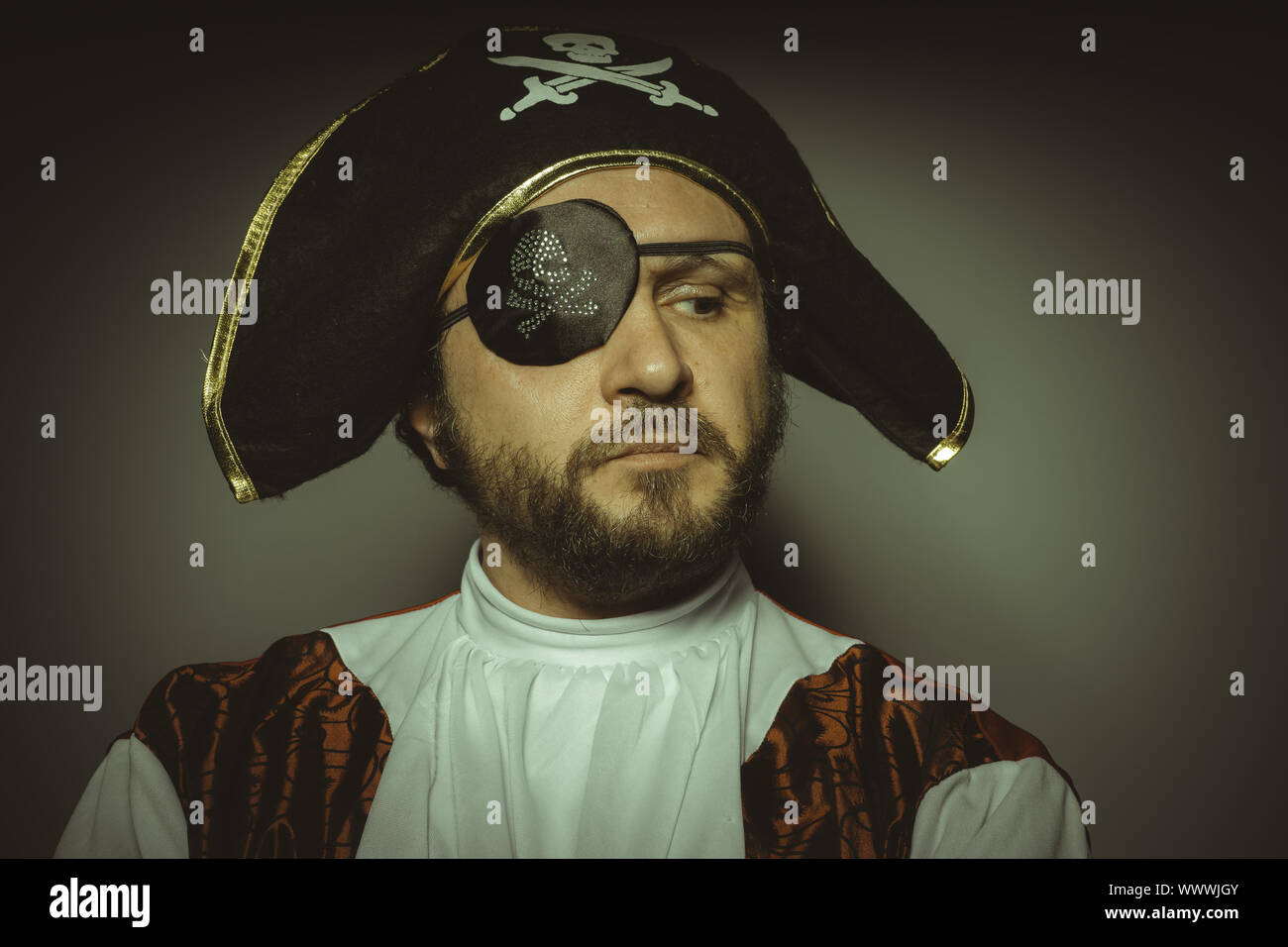 Man with beard dressed like a pirate, with eye patch and steel sword ...