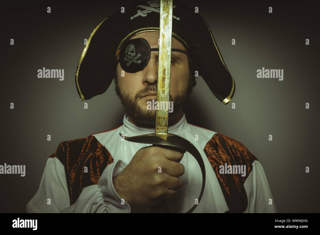 Man with beard dressed like a pirate, with eye patch and steel sword ...
