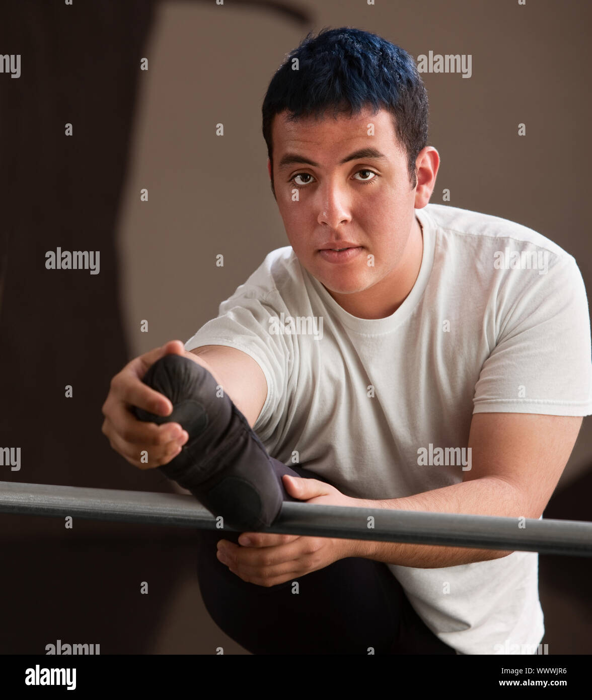 Young man stretches his leg on railing Stock Photo - Alamy