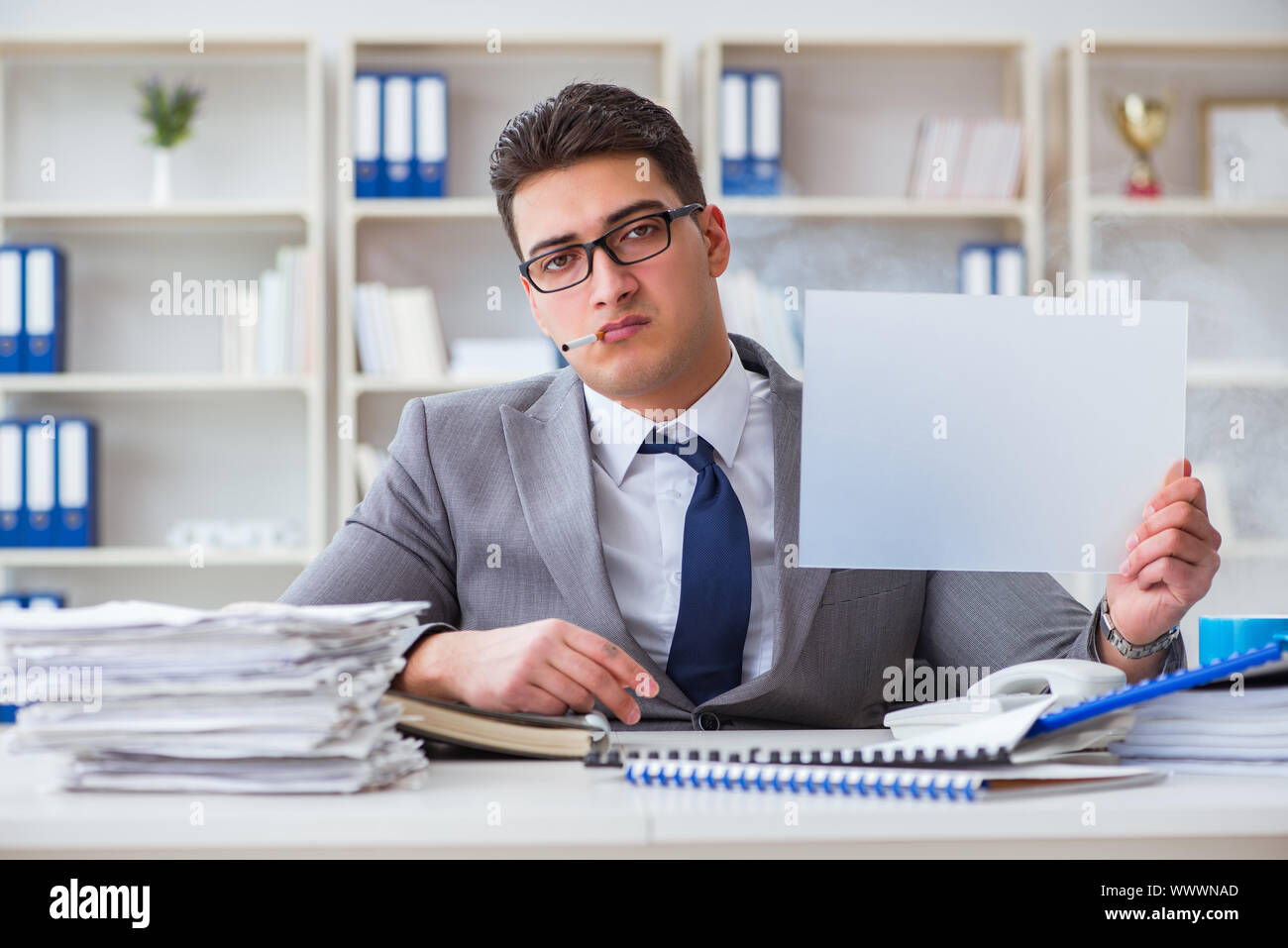Businessman smoking at work in office holding a blank message bo Stock ...
