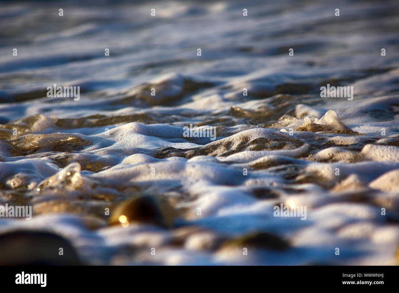 Sea rolling and receding water in rays of setting sun Stock Photo - Alamy