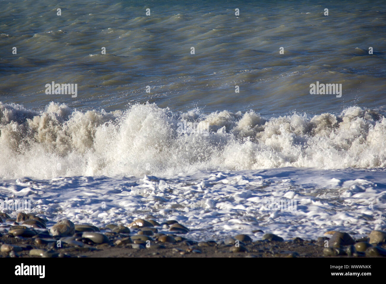 Sea rolling and receding water in rays of setting sun Stock Photo - Alamy