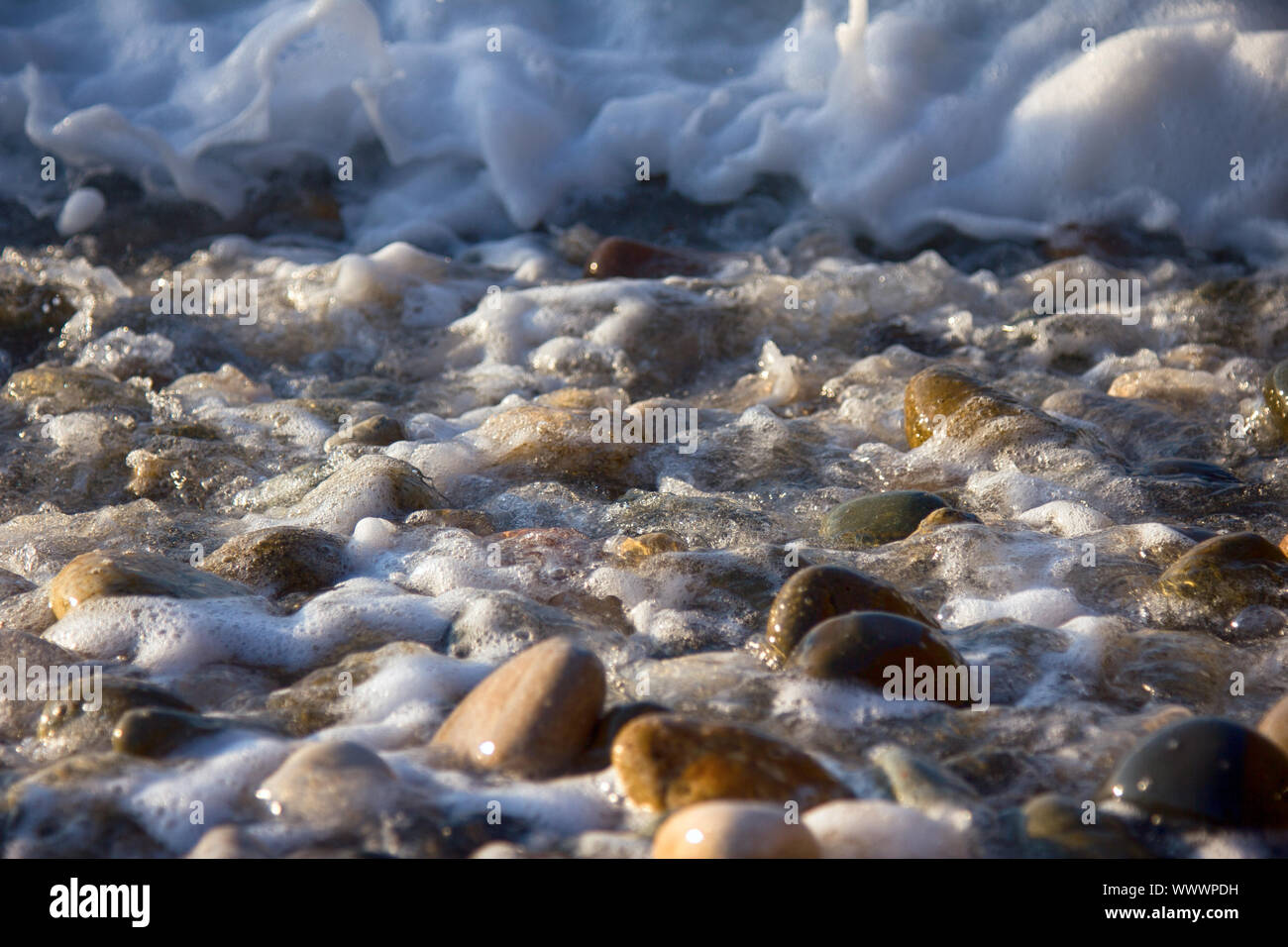 Sea rolling and receding water in rays of setting sun Stock Photo - Alamy