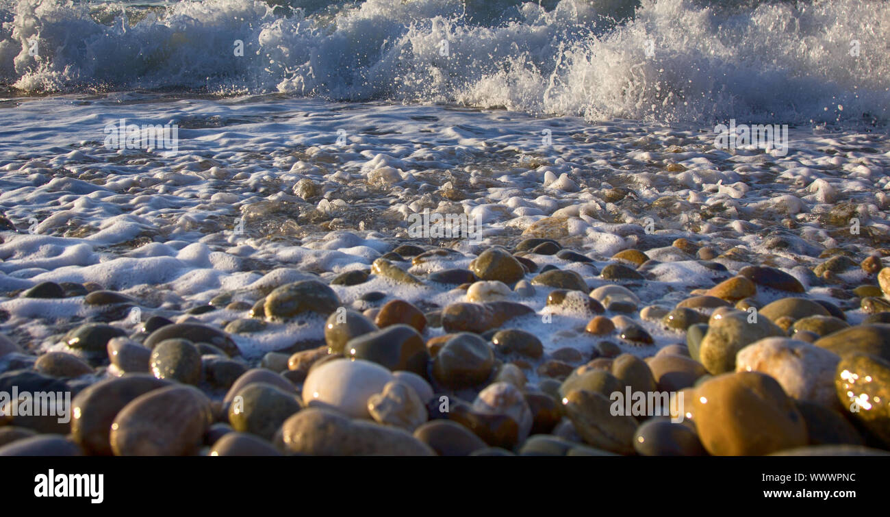 Sea rolling and receding water in rays of setting sun Stock Photo - Alamy