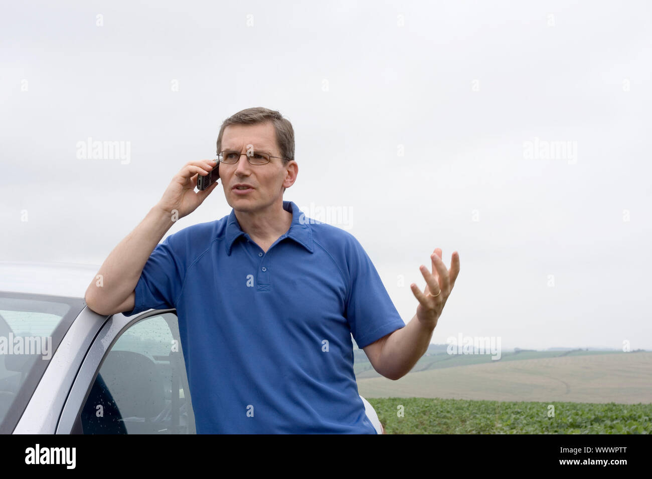 Angry man talking on cell phone beside a car Stock Photo - Alamy