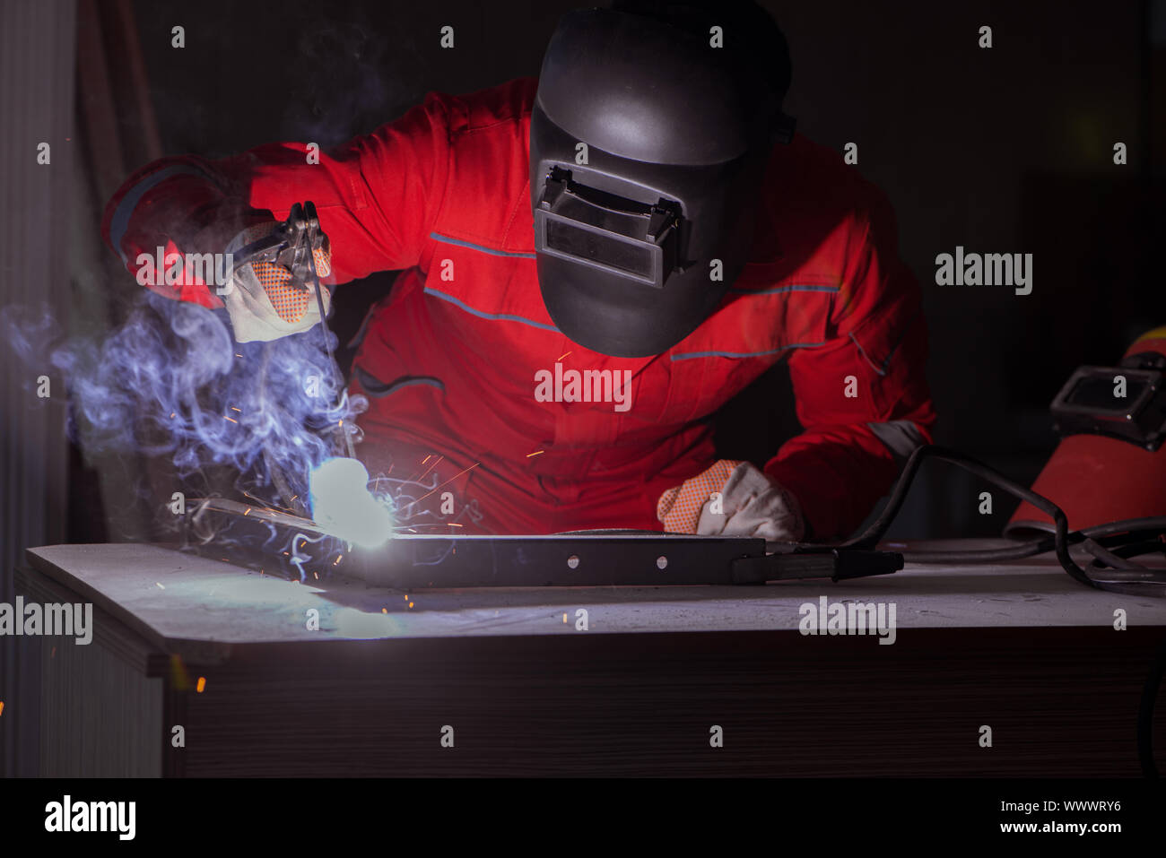 Young repairman with a welding gun electrode and a helmet weldin Stock ...