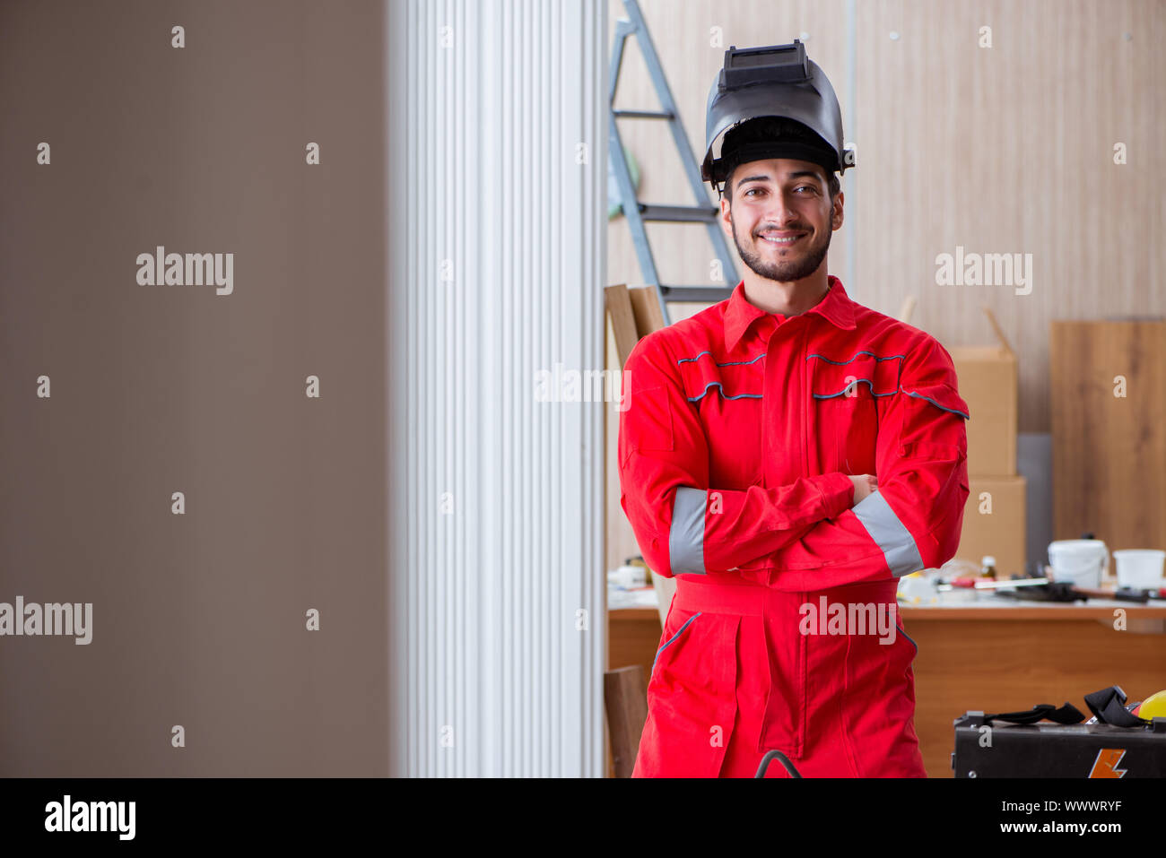 Young repairman with a welding gun electrode and a helmet weldin Stock ...