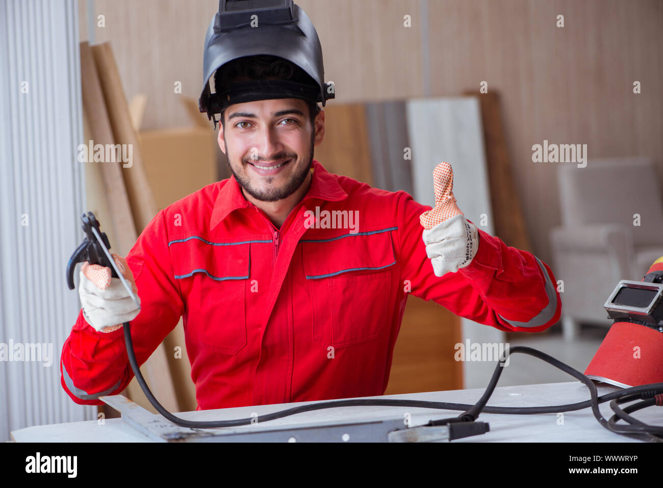 Young repairman with a welding gun electrode and a helmet weldin Stock ...