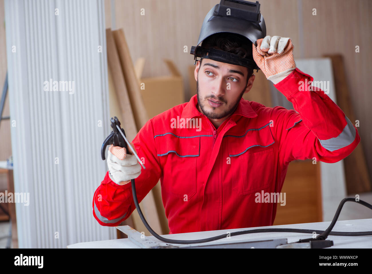 Young repairman with a welding gun electrode and a helmet weldin Stock ...