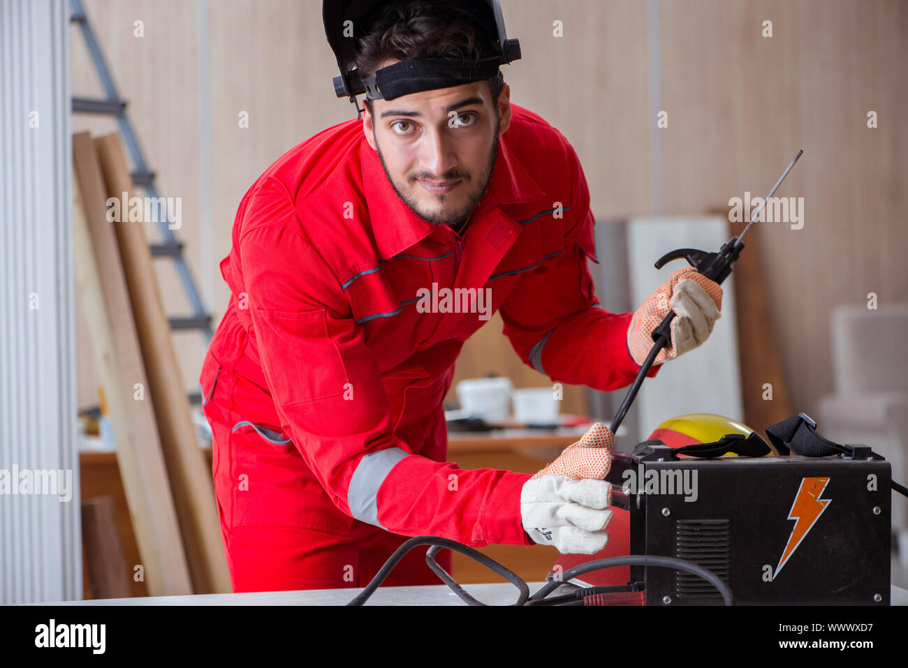 Young repairman with a welding gun electrode and a helmet weldin Stock ...