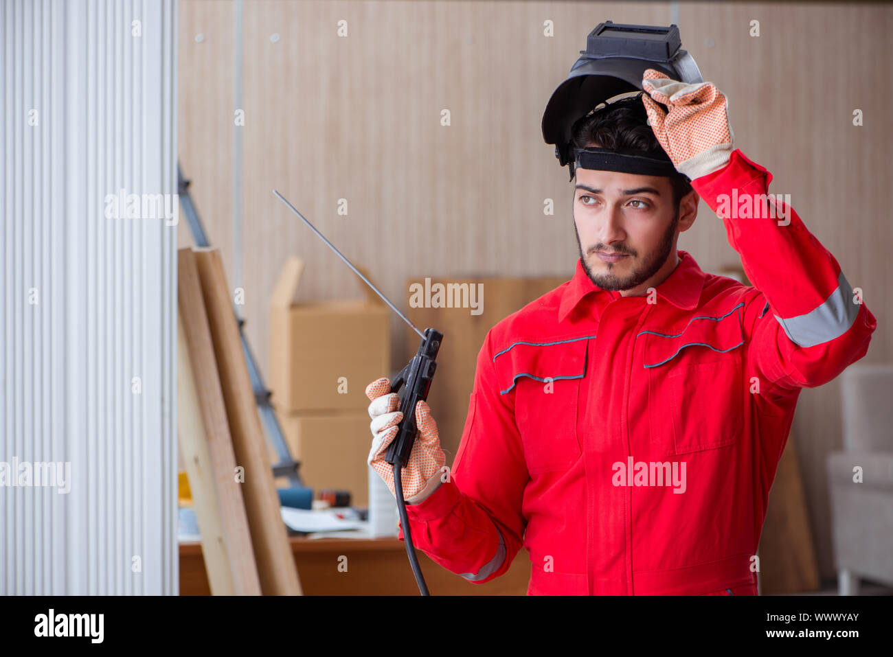 Young repairman with a welding gun electrode and a helmet weldin Stock ...