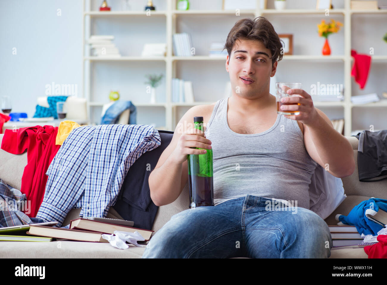 The young man student drunk drinking alcohol in a messy room Stock Photo - Alamy