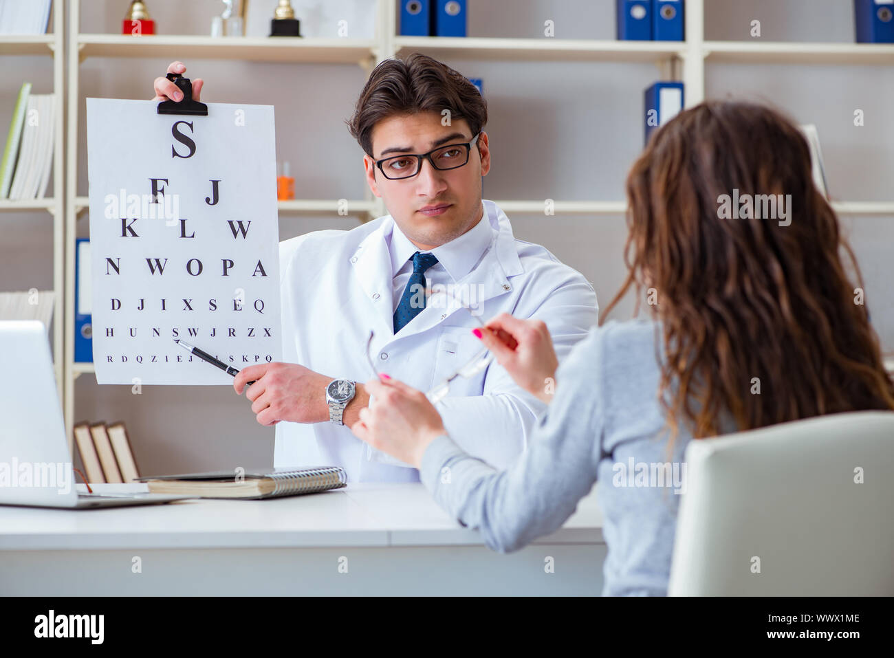 The doctor optician with letter chart conducting an eye test check ...