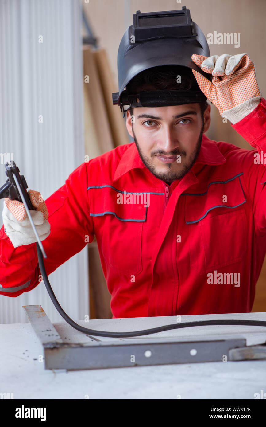Young repairman with a welding gun electrode and a helmet weldin Stock ...