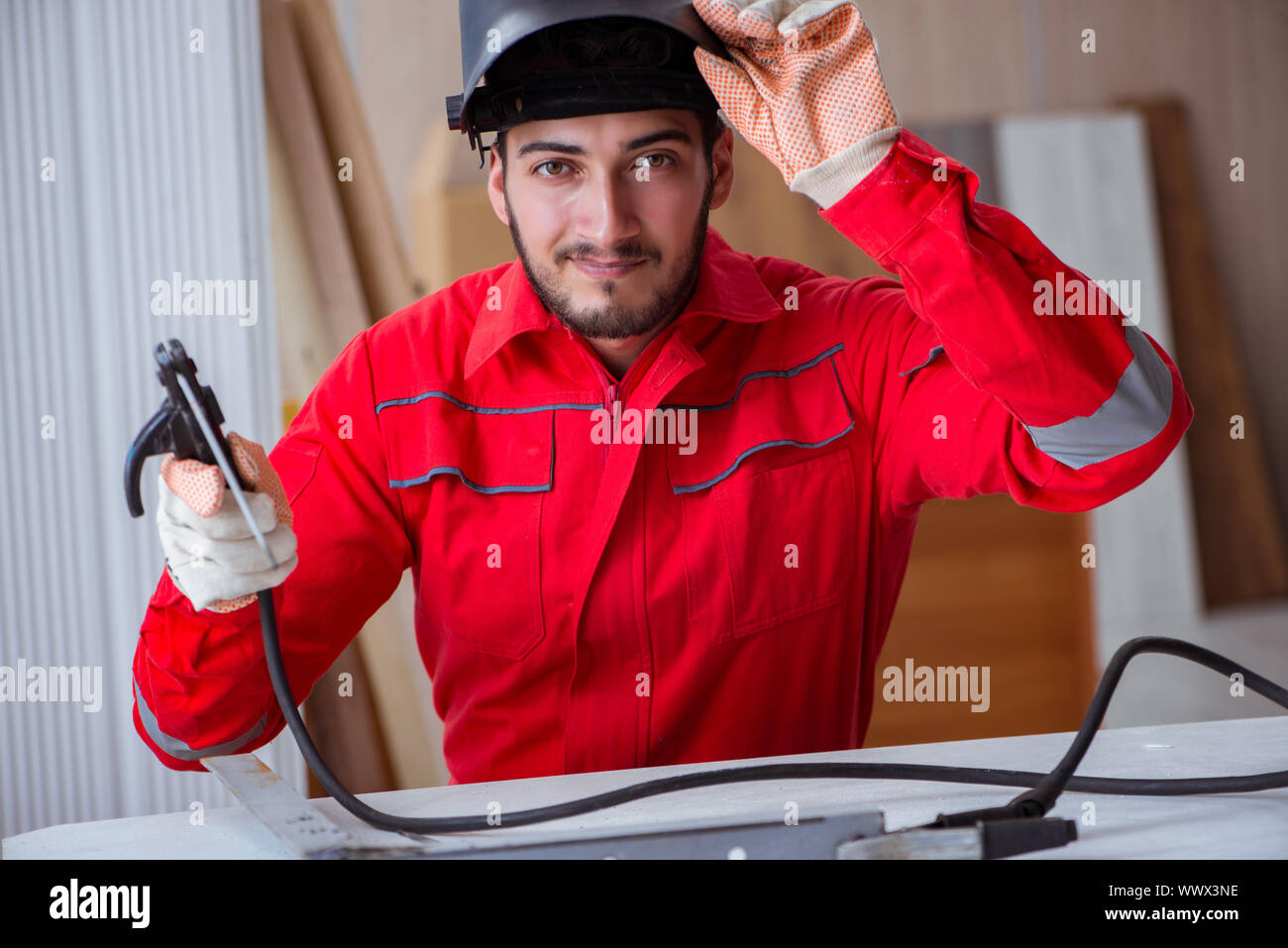 Young repairman with a welding gun electrode and a helmet weldin Stock ...