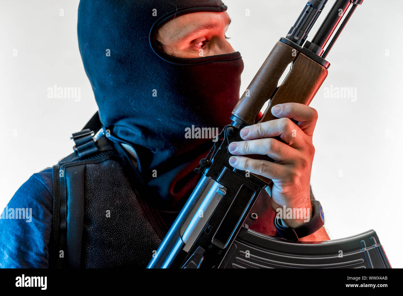 Criminal man armed with balaclava and bulletproof vest, gun and shotgun ...