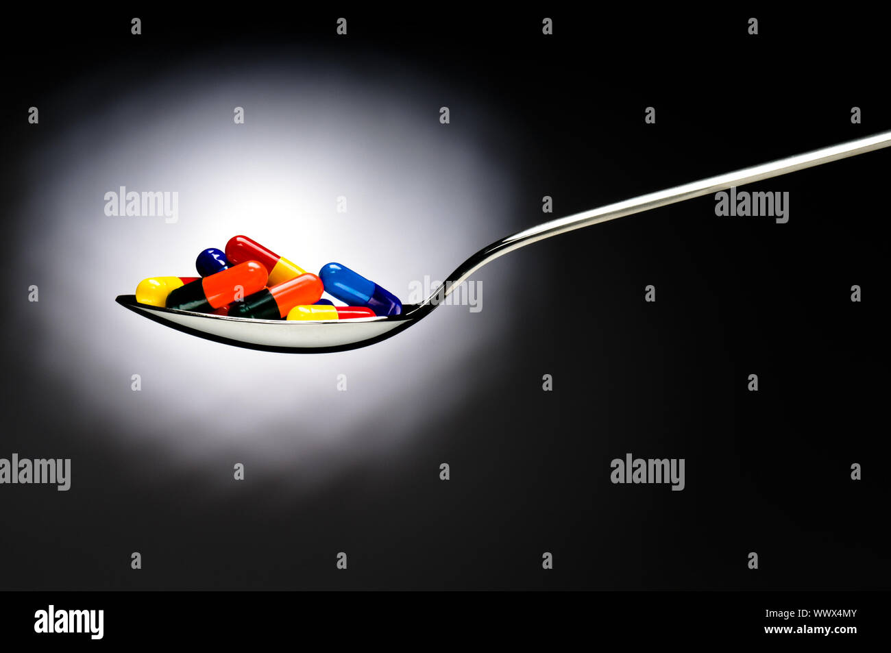 One spoon of medication in front of a black background Stock Photo - Alamy