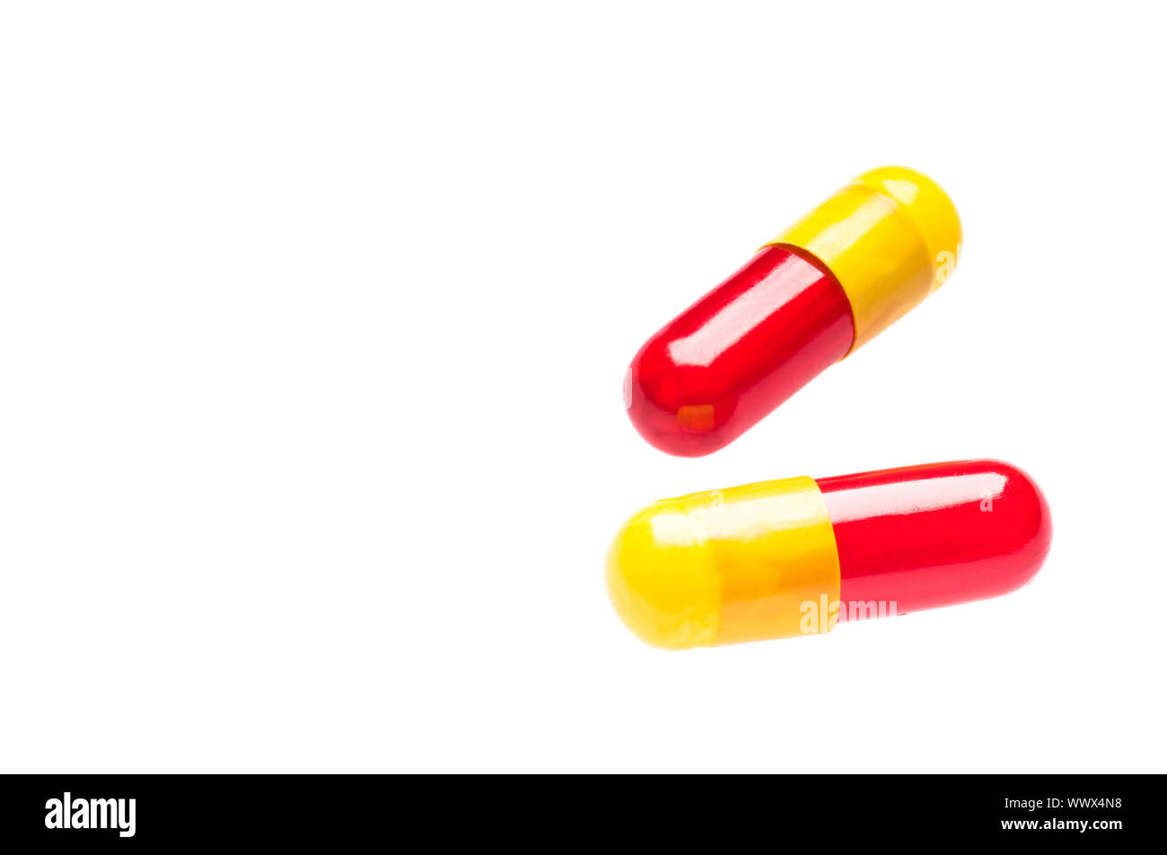 Two yellow red capsules over white Stock Photo - Alamy