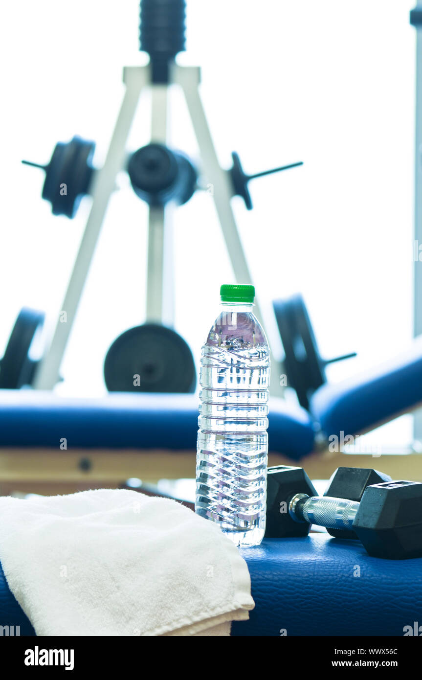 Weights stand, bench of a gym with towel and water bottle blurry ...
