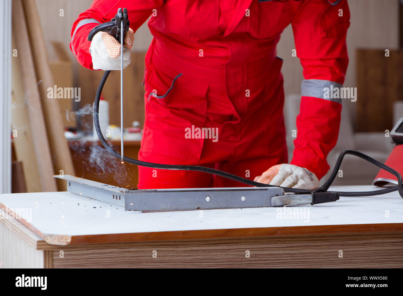 Young repairman with a welding gun electrode and a helmet weldin Stock ...