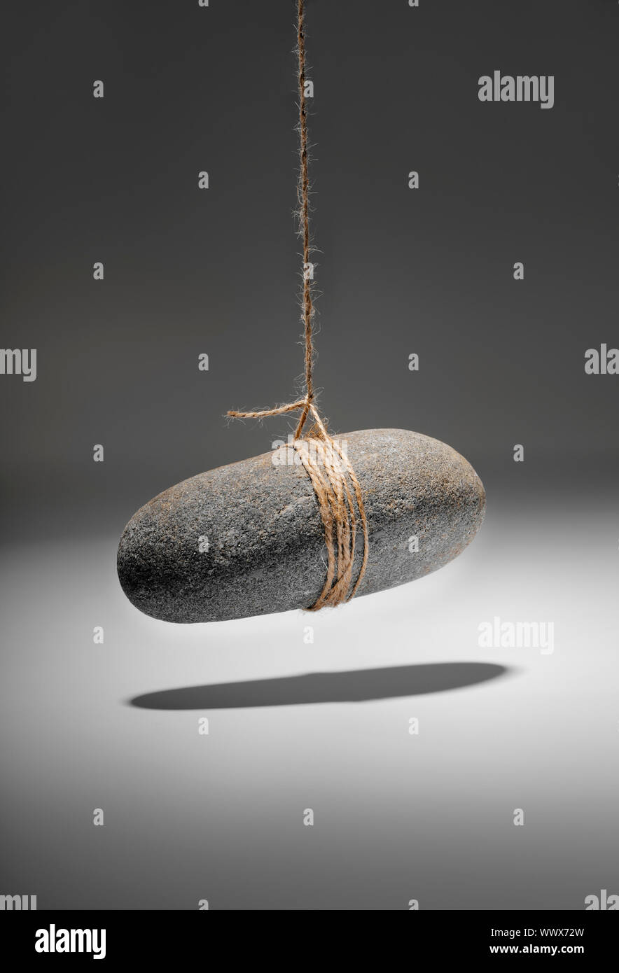 Conceptual image of a small rock hanging on a string Stock Photo - Alamy