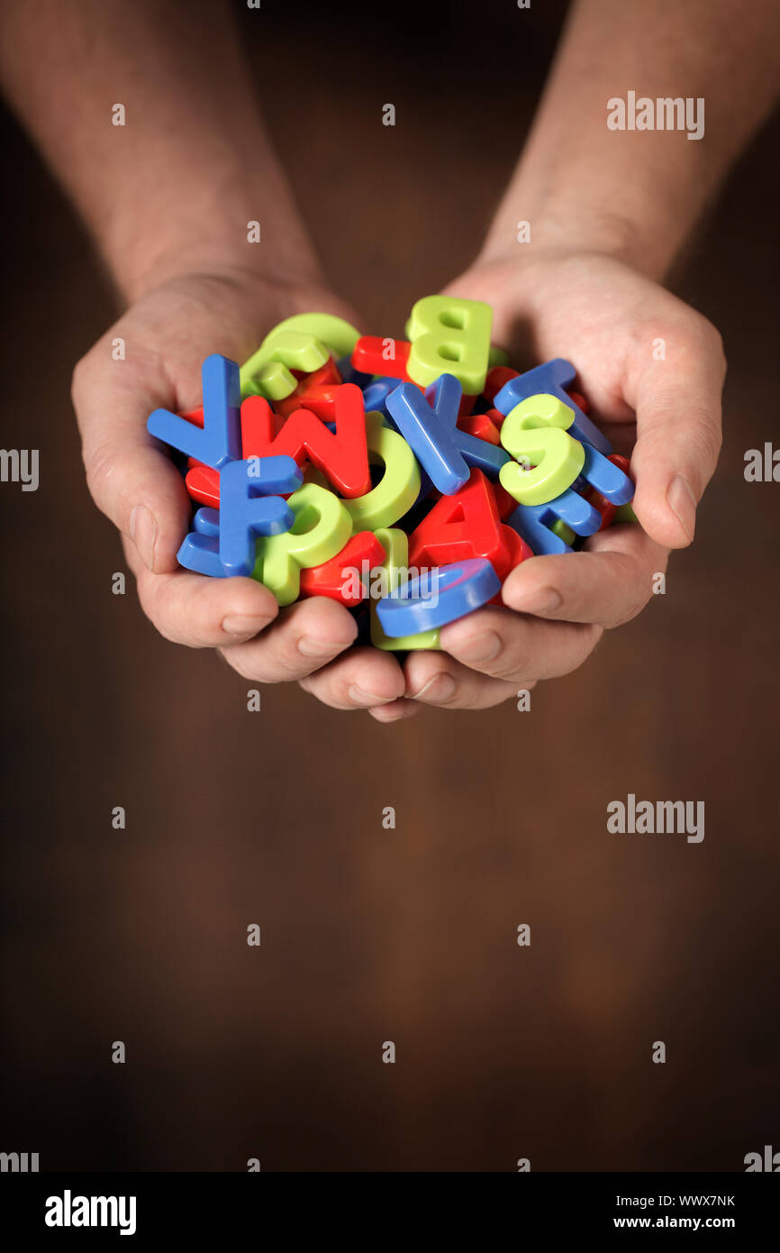 Man holding colorful plastic toy letters in his hands Stock Photo - Alamy