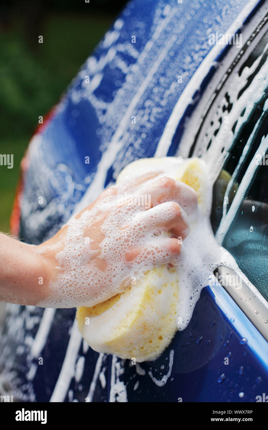 A Hand washing a blue car with a sponge Stock Photo - Alamy