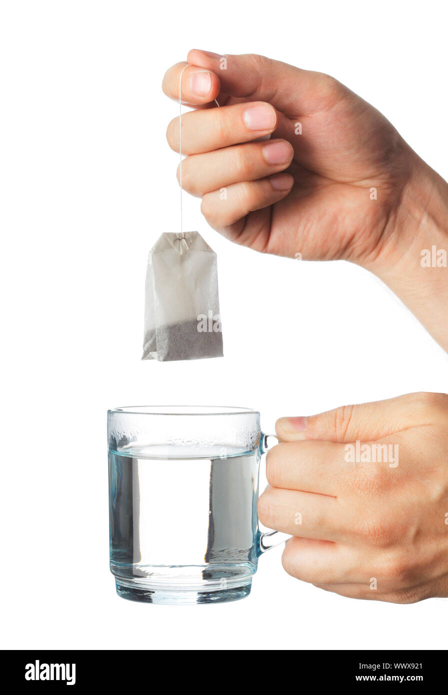 Hand putting a tea bag into a transparent glass cup of hot water Stock ...