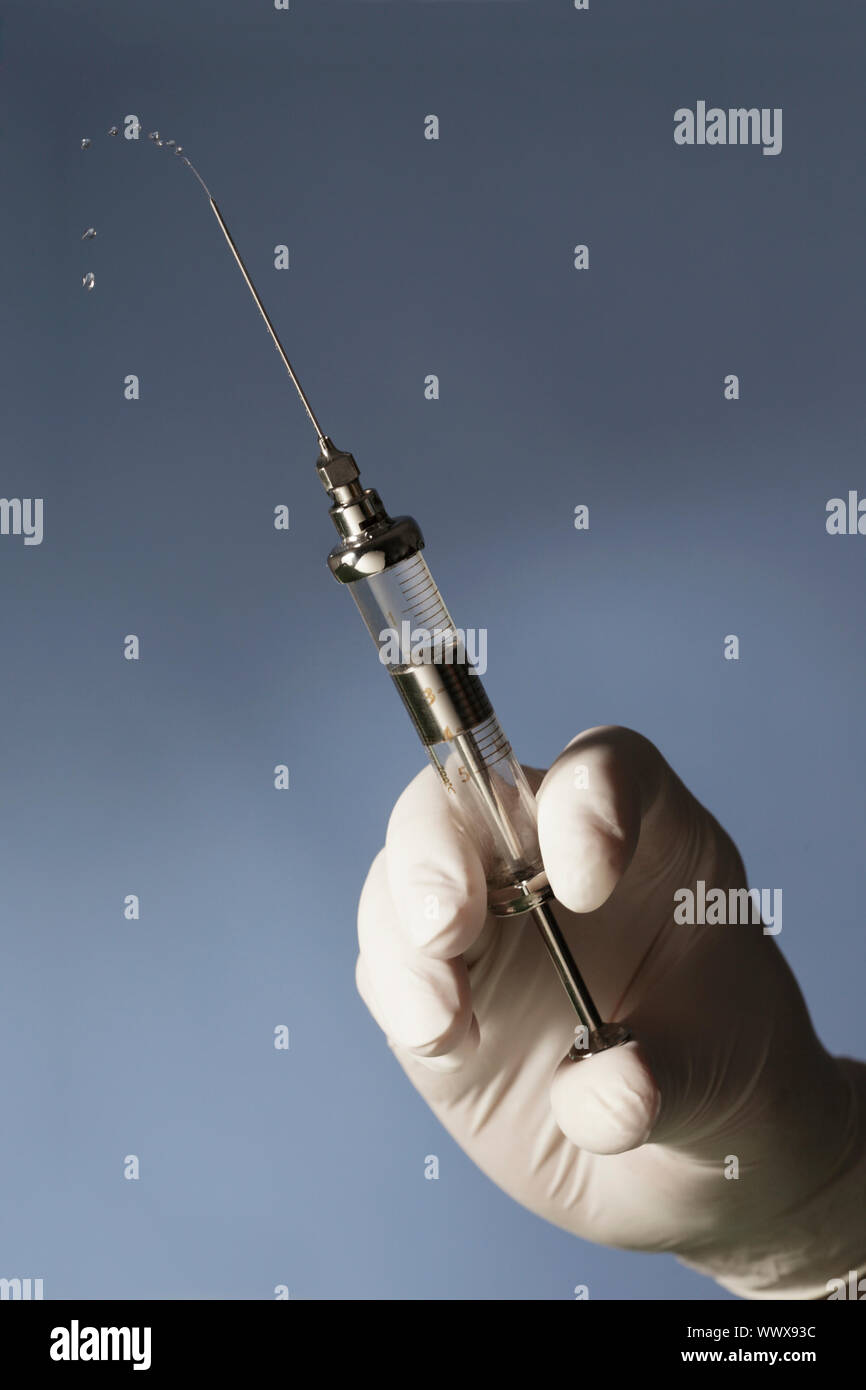 Hand squeezing an old glass syringe with a sharp needle Stock Photo - Alamy