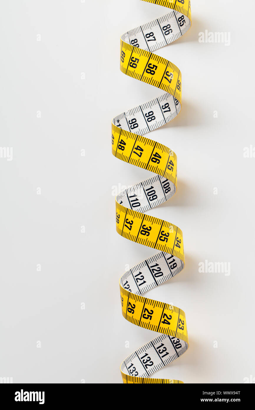 Yellow tape measure on light grey background Stock Photo - Alamy