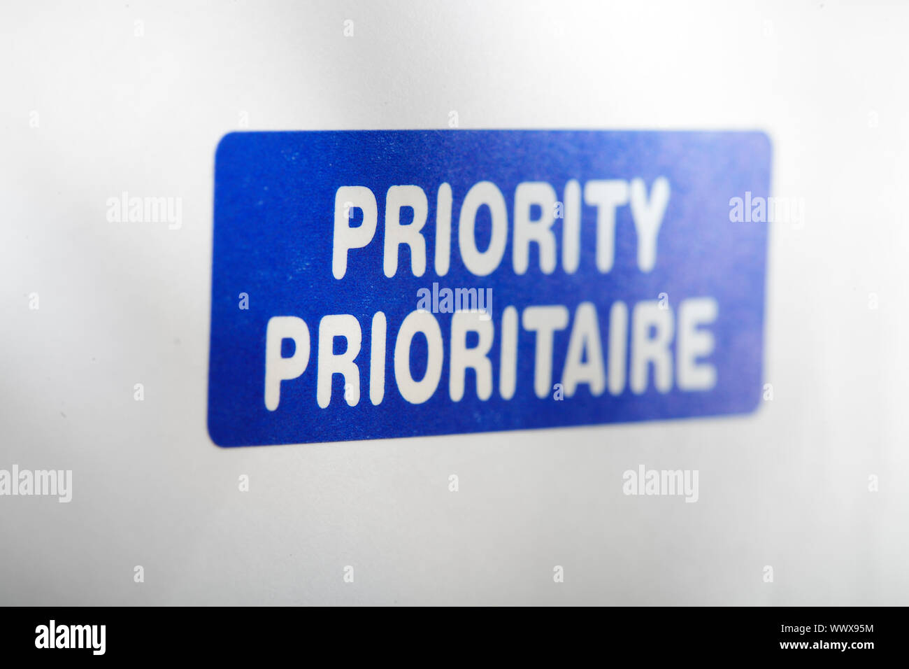 A blue "Priority" sticker on an envelope. Short depth-of-field Stock ...