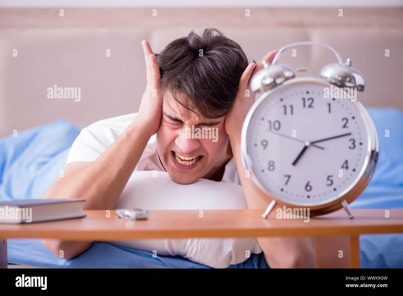 Man in bed frustrated suffering from insomnia with an alarm cloc Stock ...