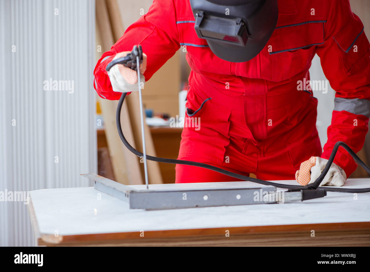 Young repairman with a welding gun electrode and a helmet weldin Stock ...