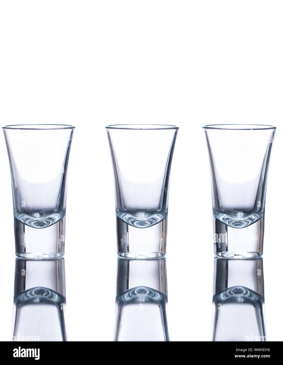 Three empty shot glasses on a reflective surface. Isolated on white ...