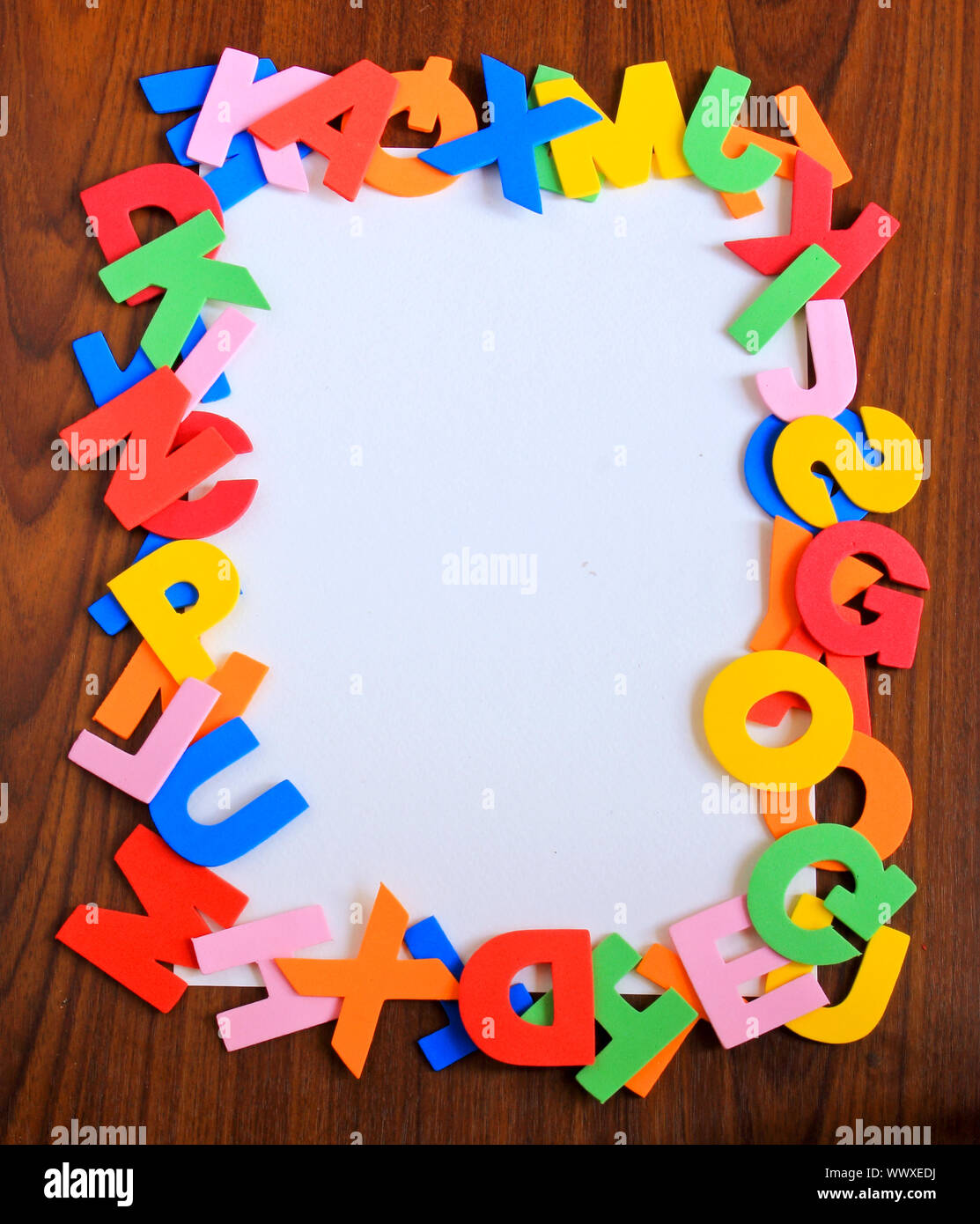 Colorful alphabet as frame with white paper on wooden background Stock ...