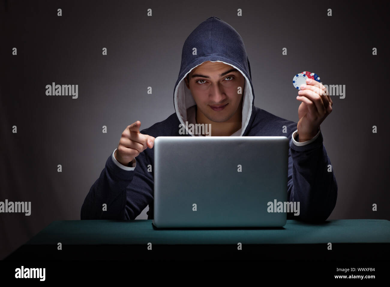 Young man wearing a hoodie sitting in front of a laptop computer Stock ...