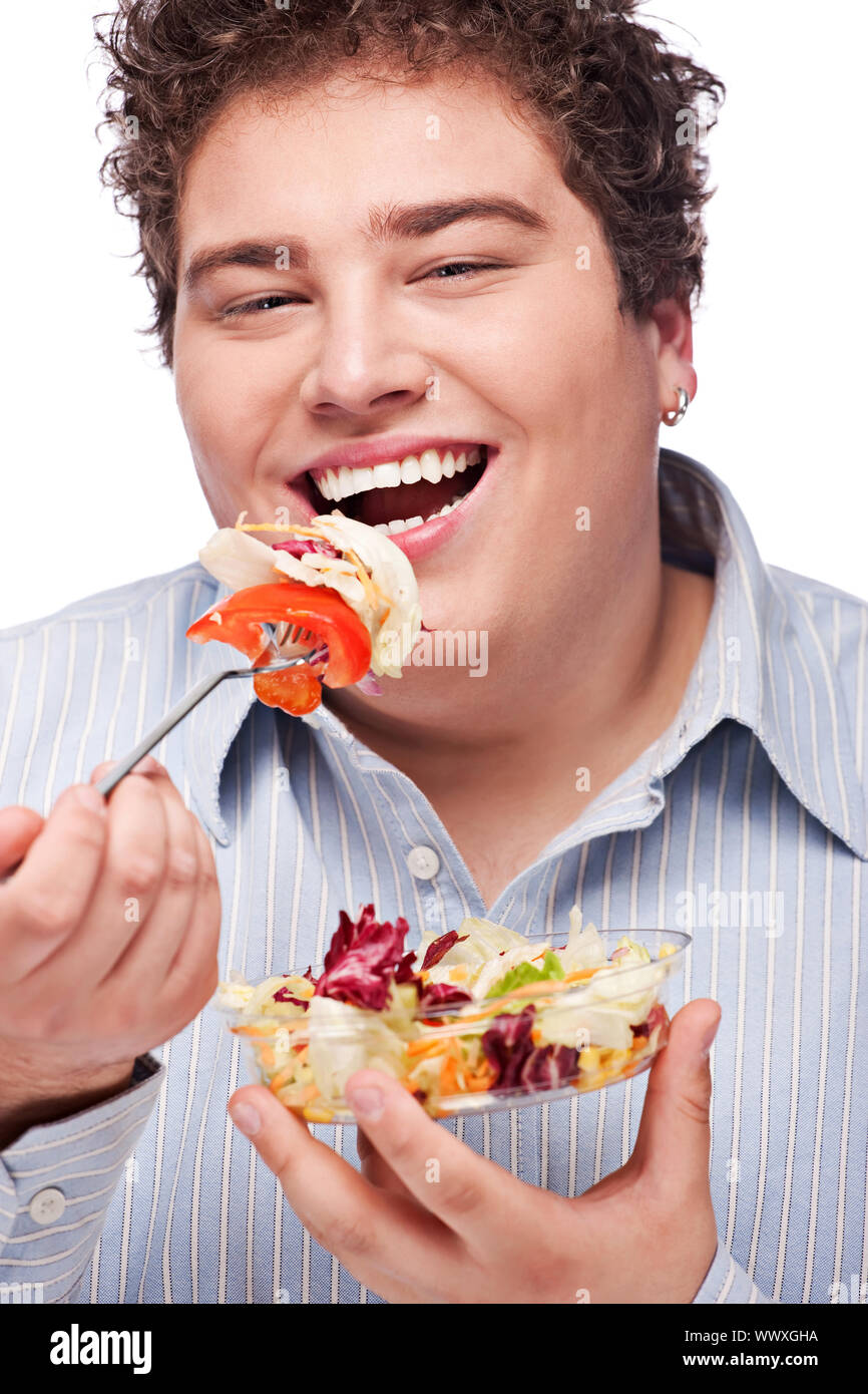 Happy young chubby man eating fresh salad with fork, isolate on white ...