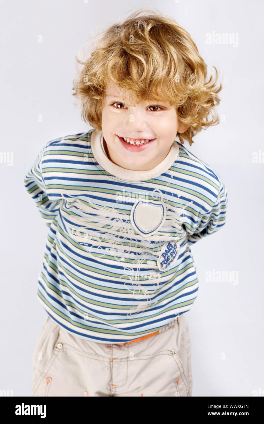 Smiled boy hiding something behind his back Stock Photo - Alamy