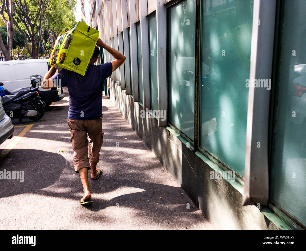 Man walking on a sidewalk, carrying a heavy bag, Marseille, Bouches-du ...