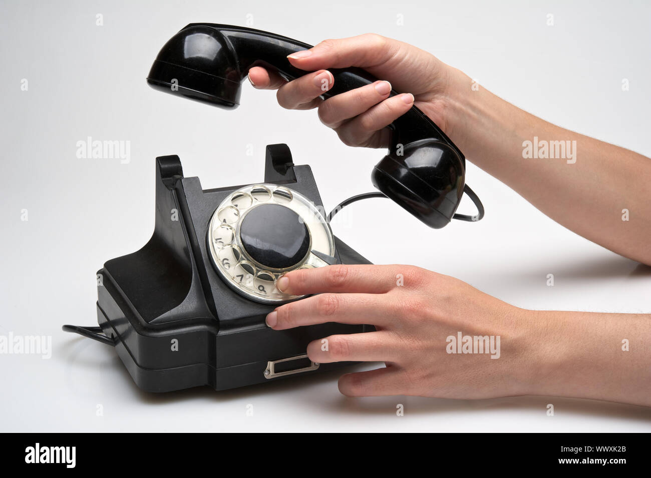 woman hand hanging up the handset of an old black telephone isolated ...