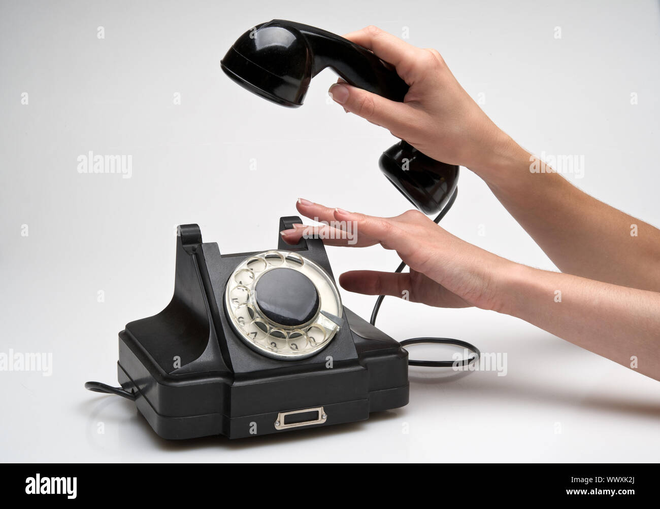 woman hand hanging up the handset of an old black telephone isolated ...