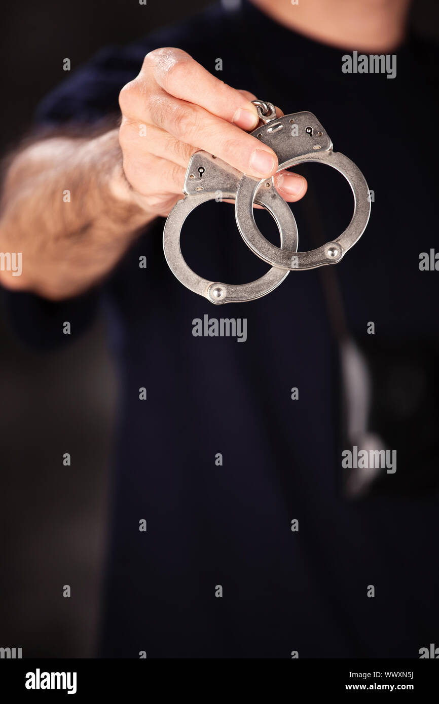 Handcuffs in male officer's hand Stock Photo - Alamy