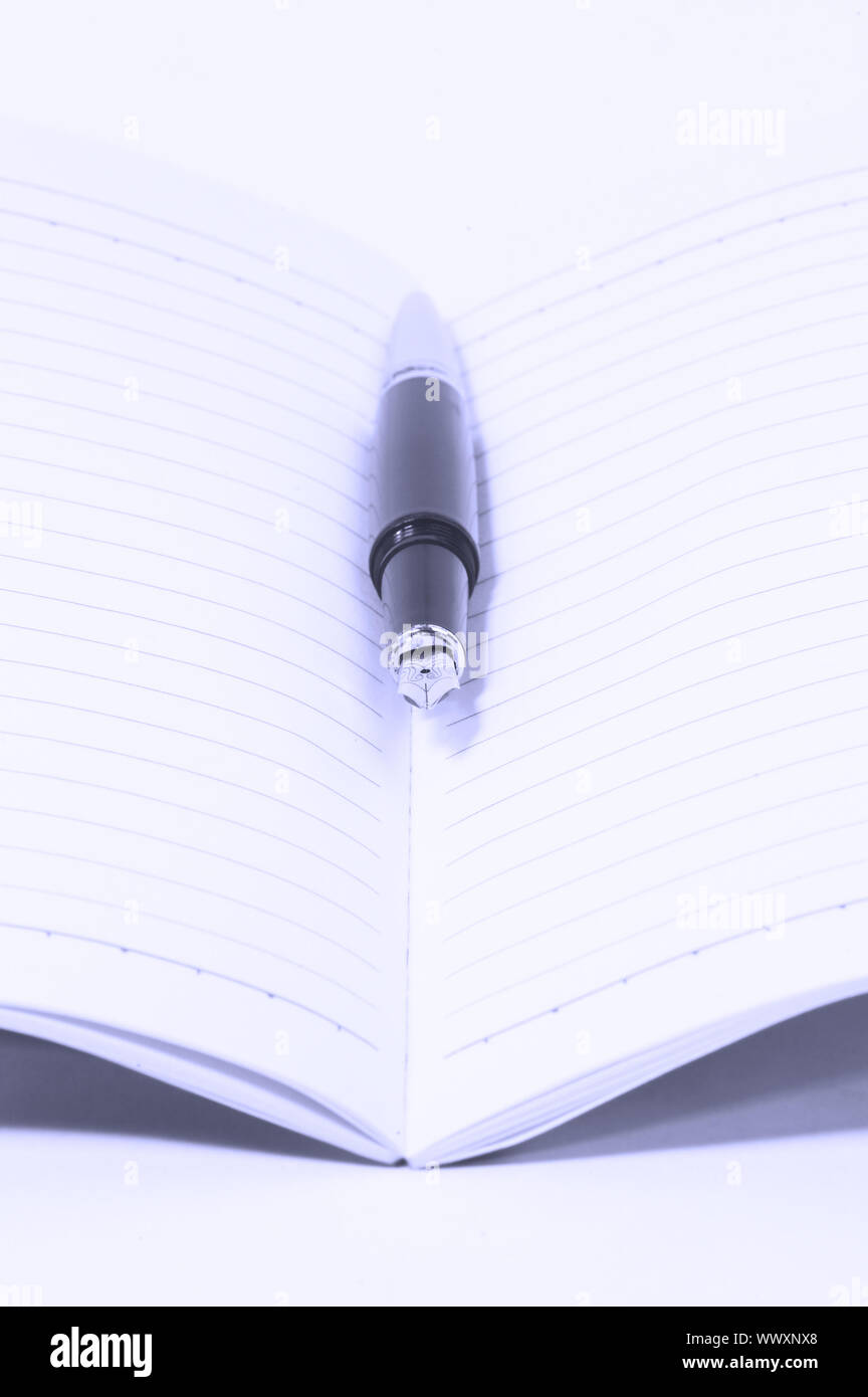 classic black fountain pen on open notebook,blue filter Stock Photo - Alamy