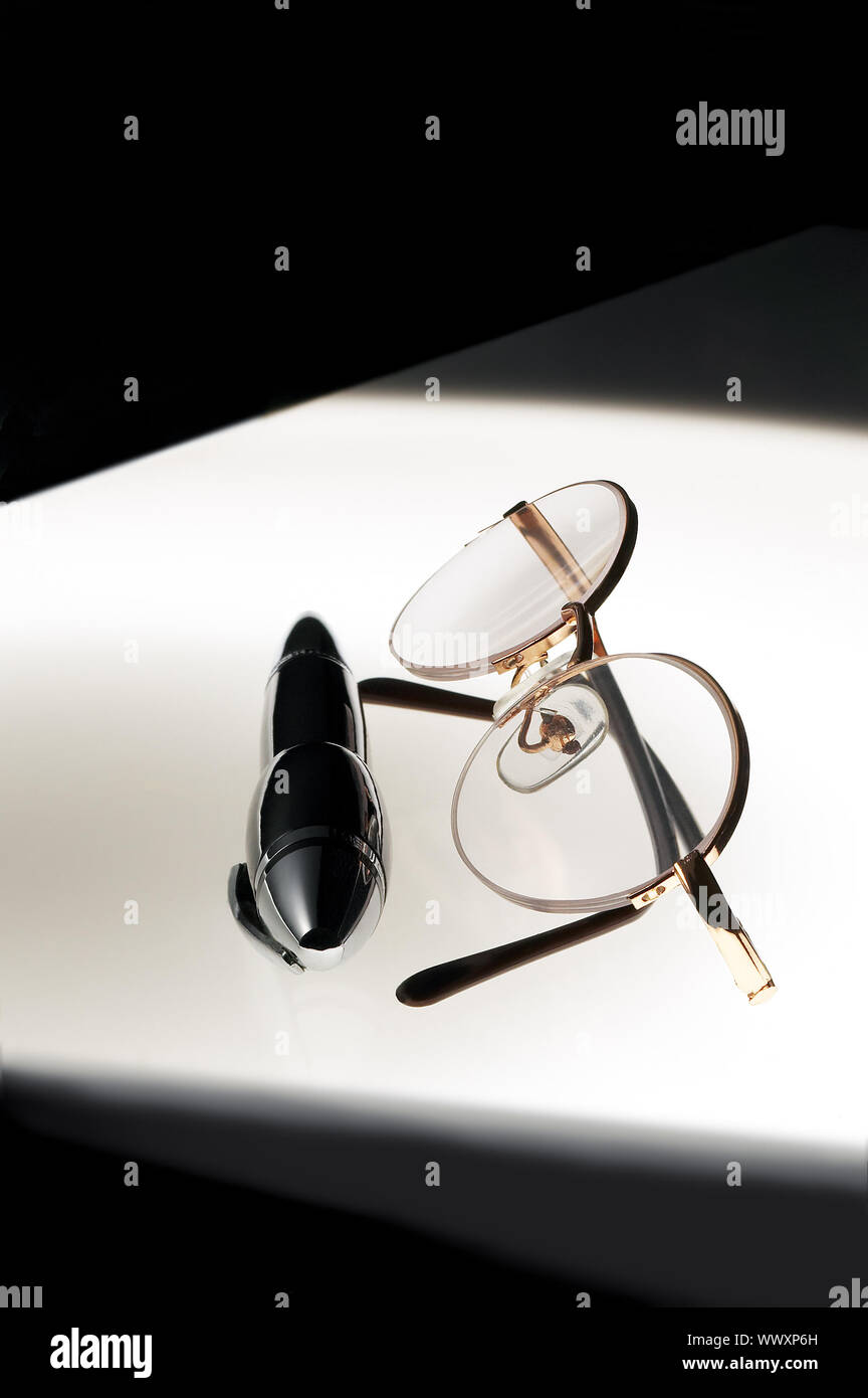pen and glasses over white glass table Stock Photo - Alamy