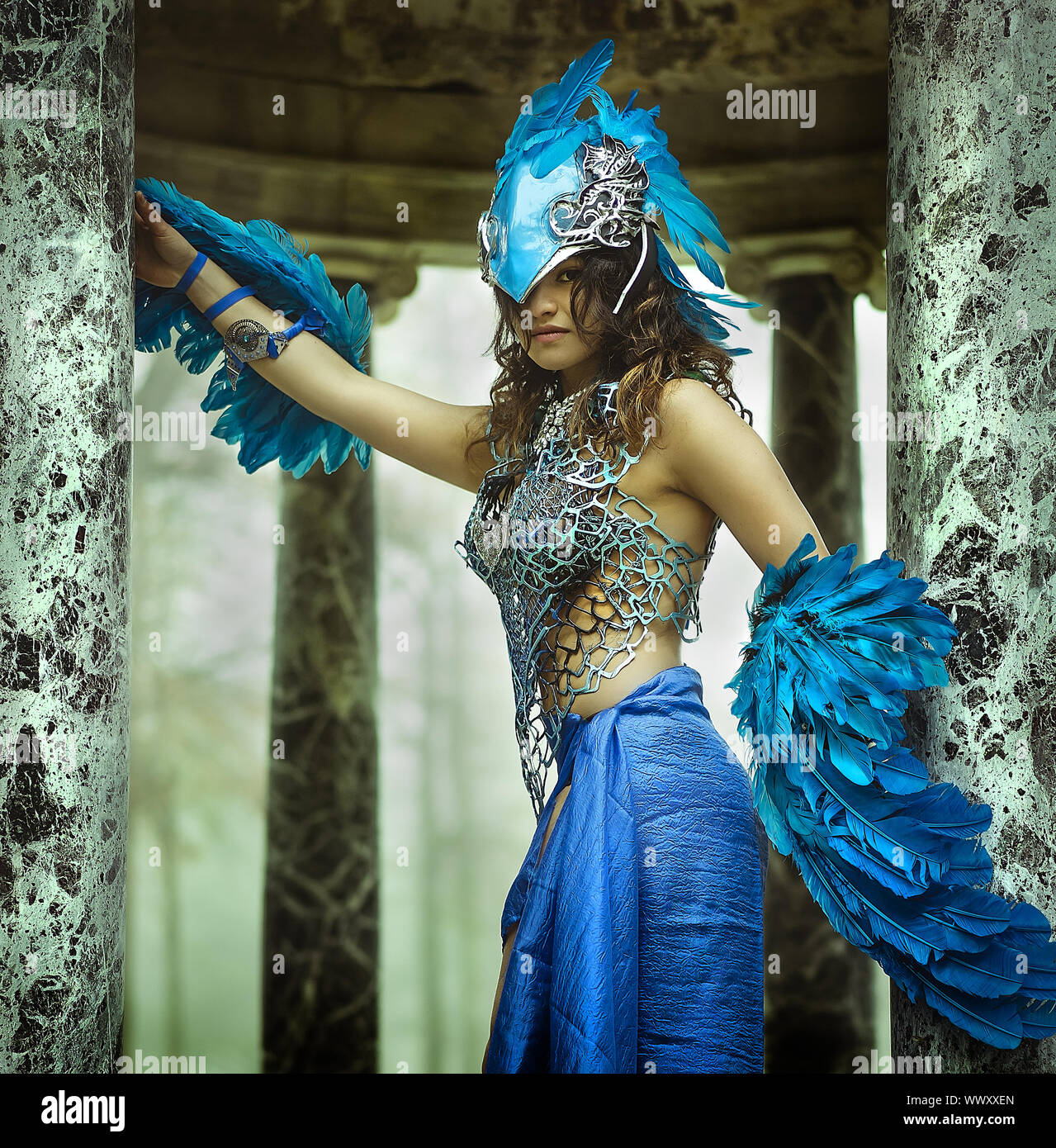 Gothic beautiful brunette girl in a suit made of blue wires, bears bird ...