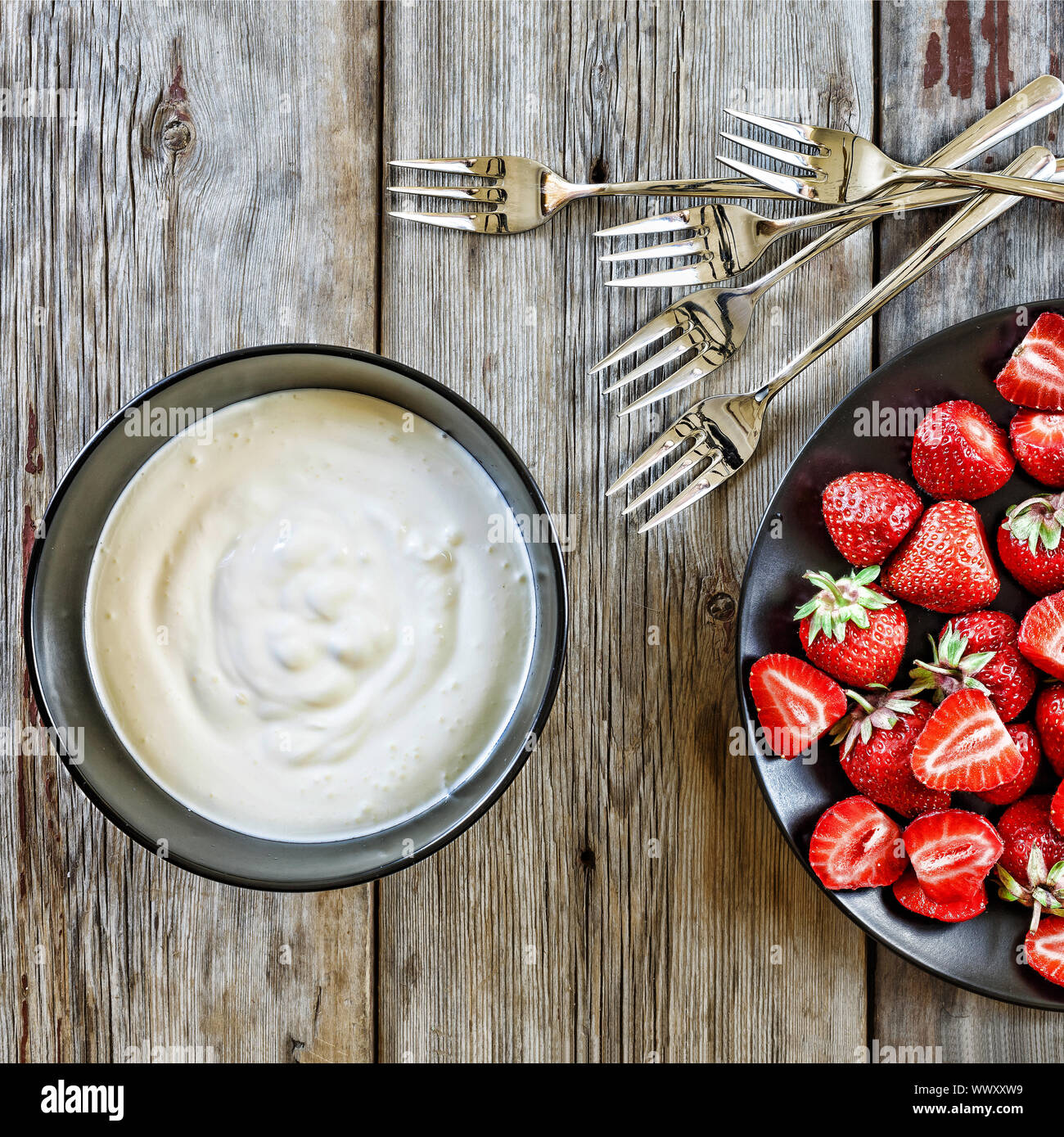 Ripe tasty strawberries on a black plate on a wooden table. View from ...