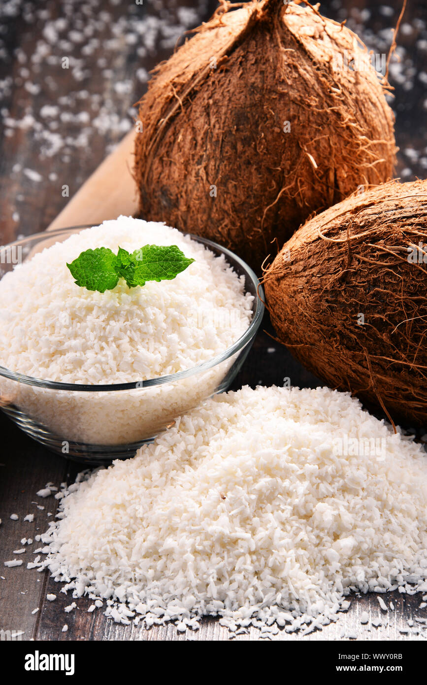 Composition with bowl of shredded coconut and shells on wooden table ...